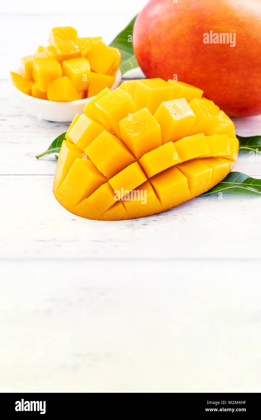 Beautiful chopped mango with green leaves on bright white color timber ...