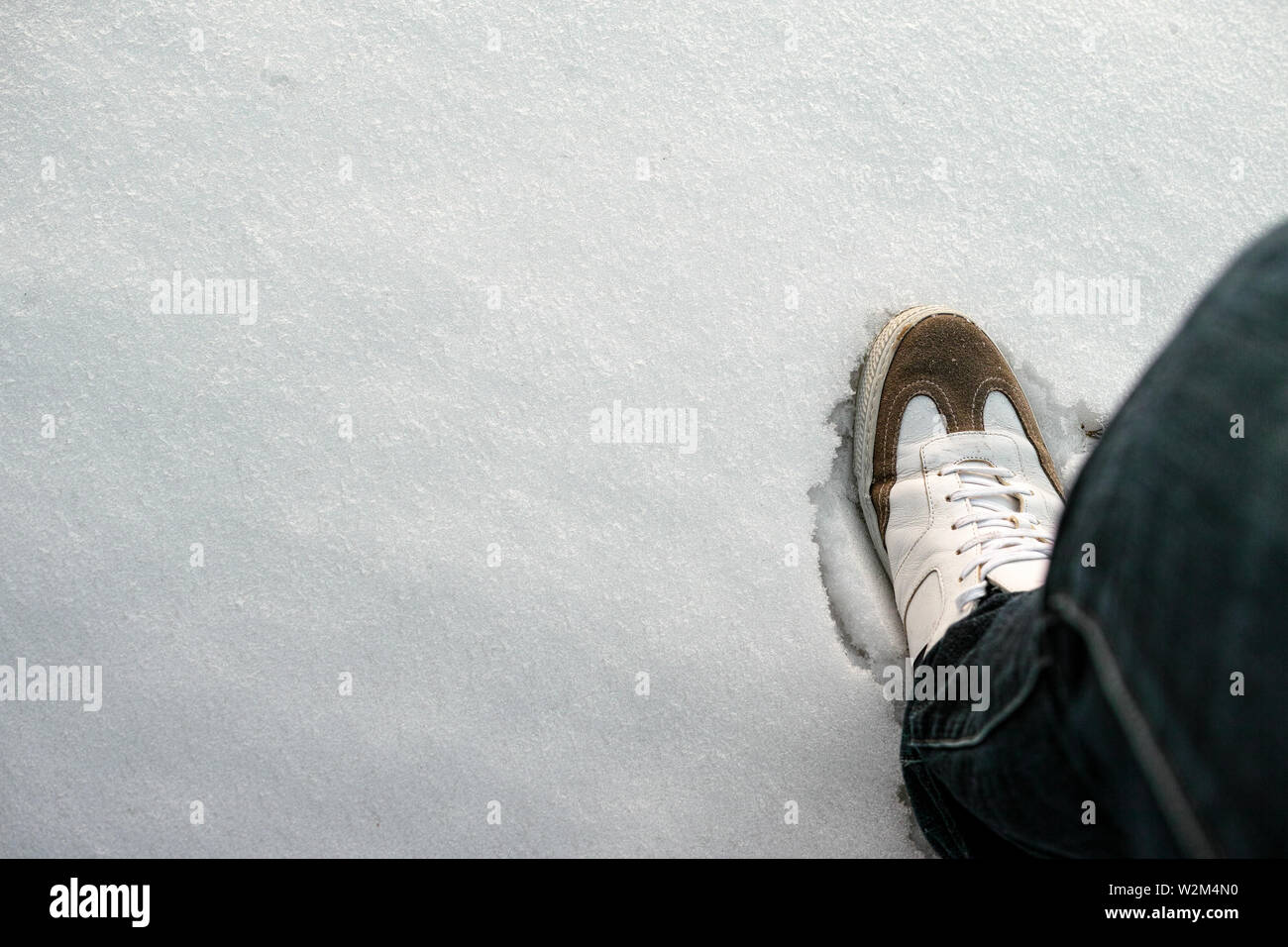 A shoe stepping on frozen ground Stock Photo - Alamy