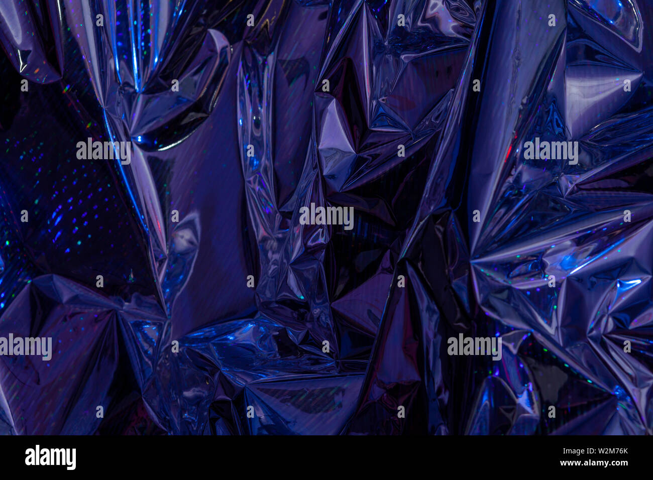 The background of crumpled holographic packaging film with an abstract ...