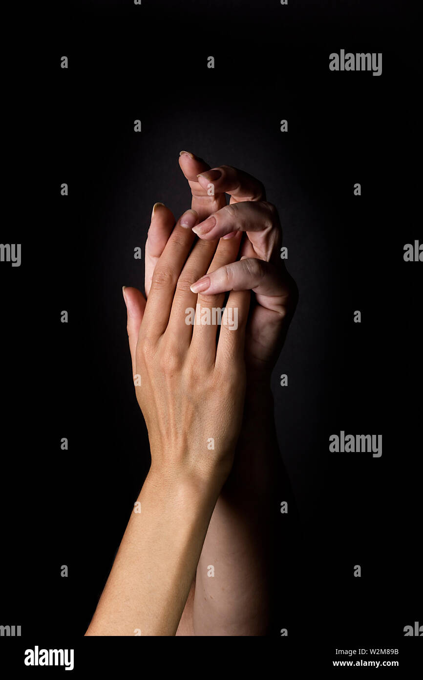 Two entwined female hands on a black background Stock Photo - Alamy