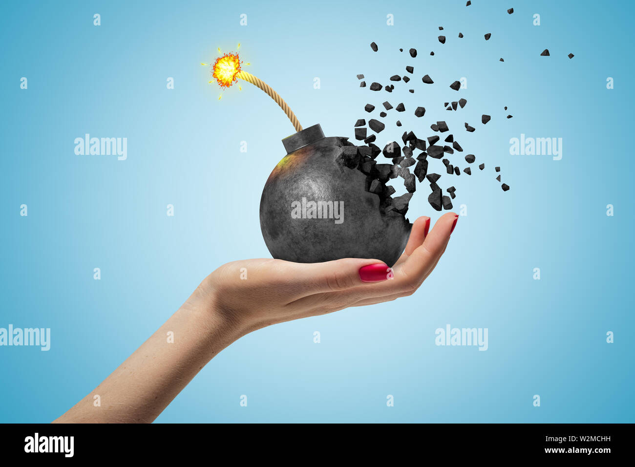 Female hand holding black burning bomb shattering into pieces on blue ...