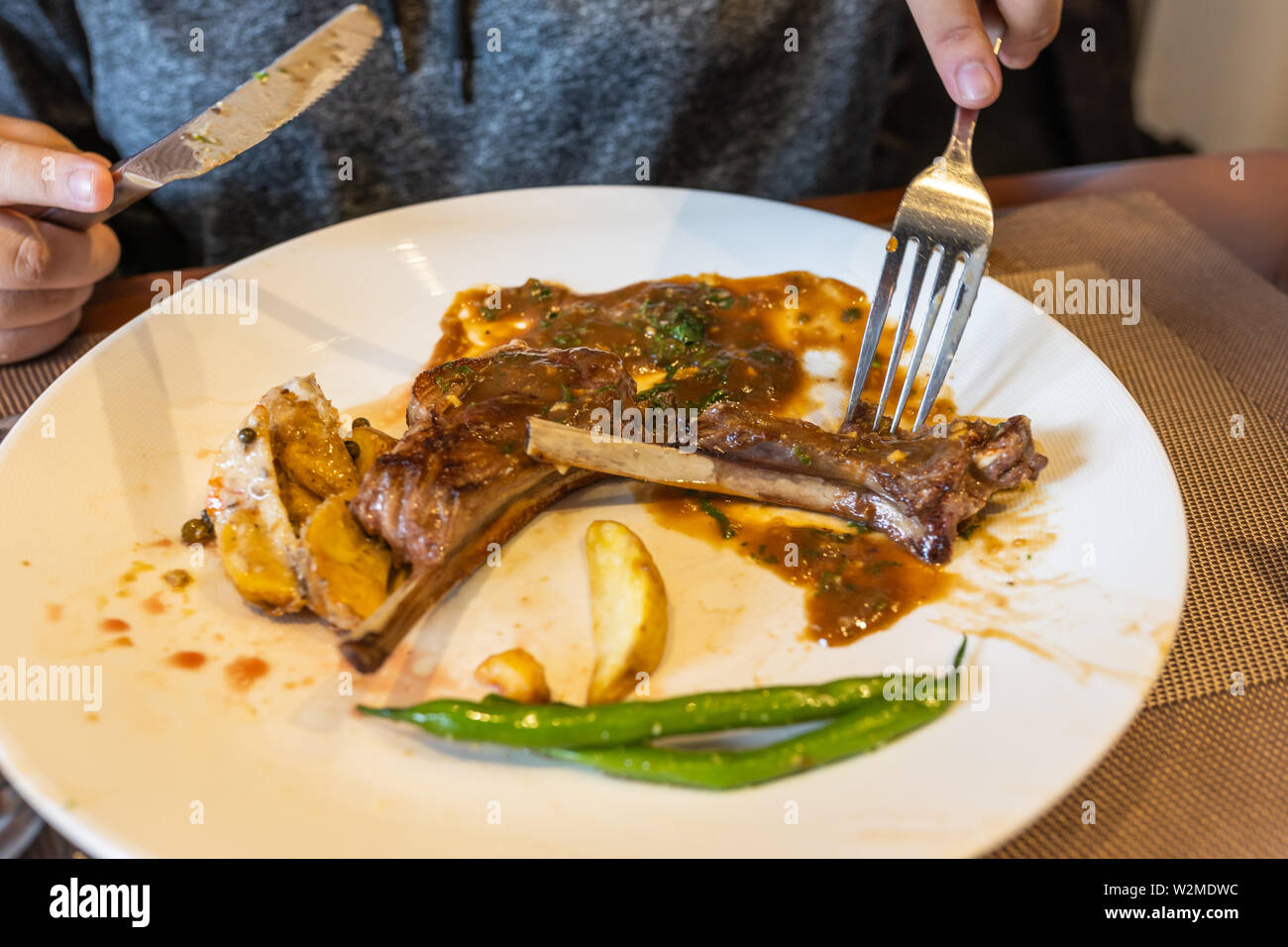 Closeup of hands using knife and folk while eating steak Stock Photo ...