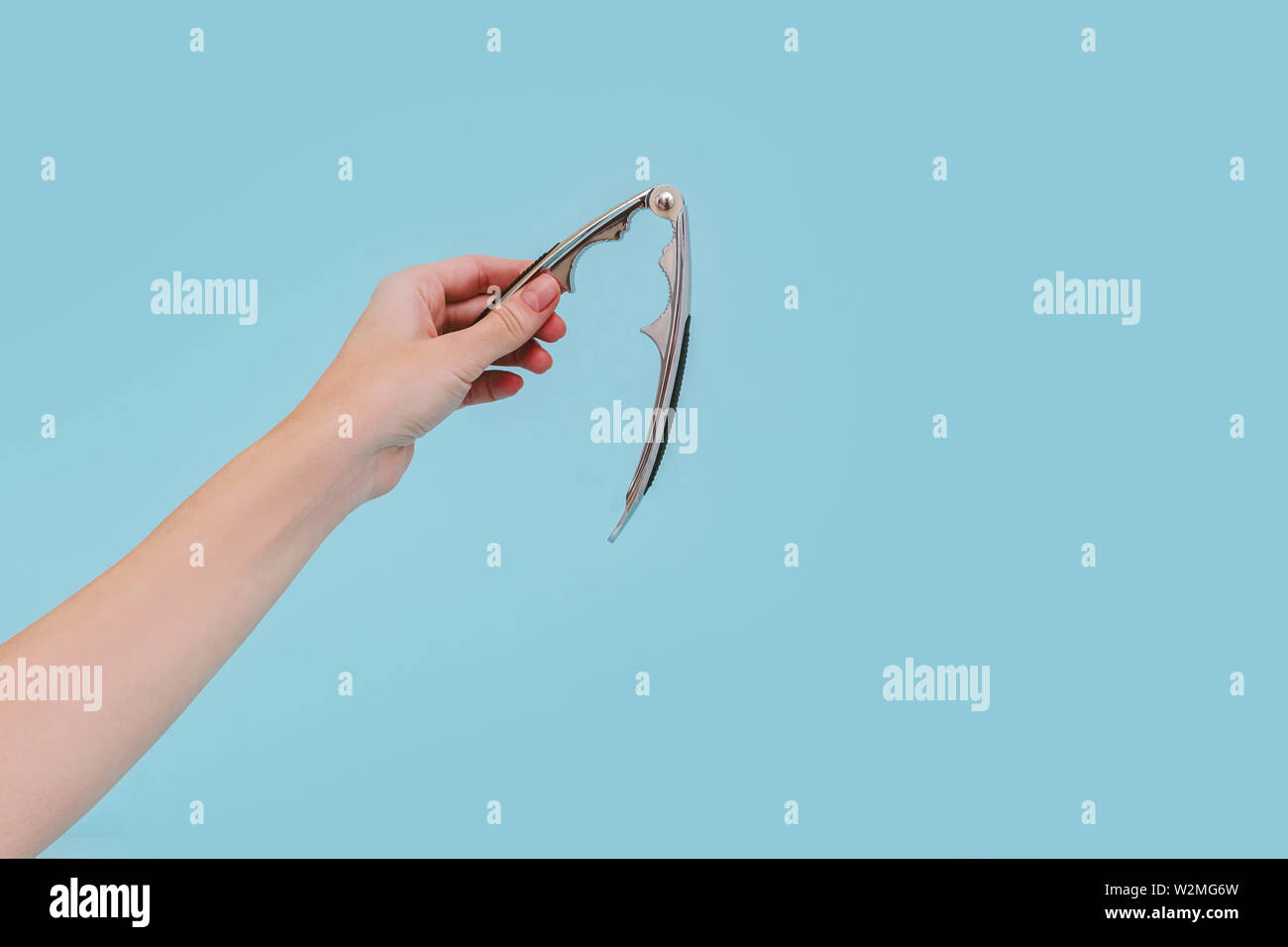 Nutcracker in woman's hand on blue background Stock Photo - Alamy