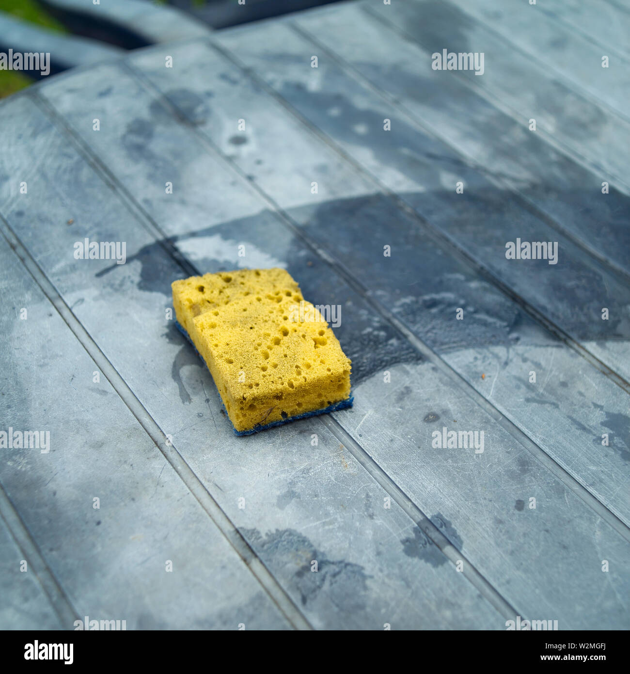Removing grease and dirt with a sponge from the plastic table, outdoor ...