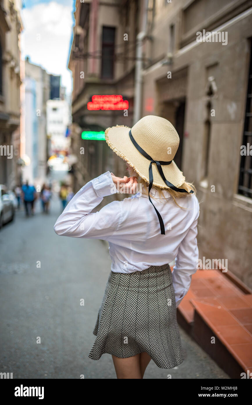 Back view of attractive fashionable girl with trendy clothes and hat ...