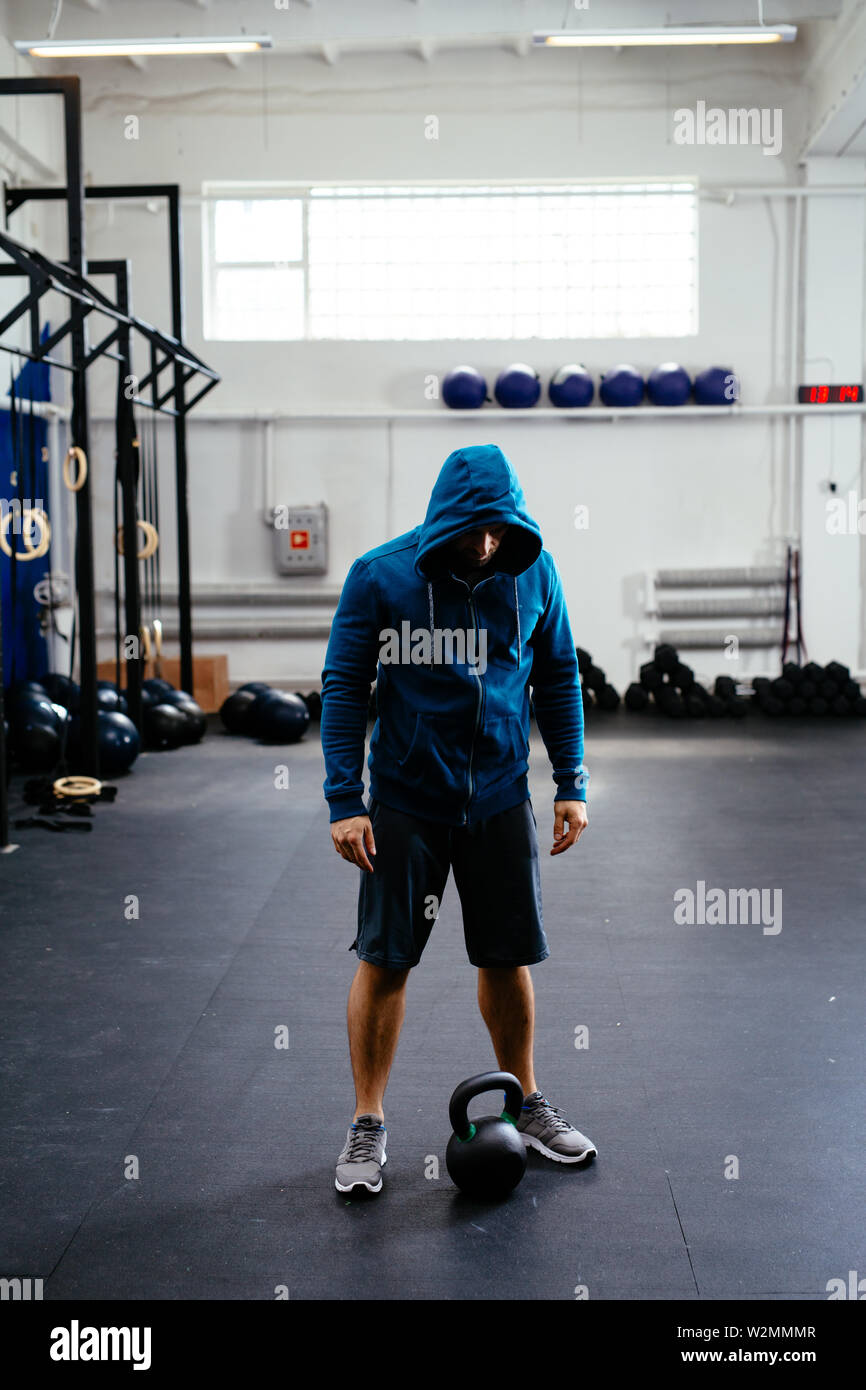 Muscular man standing in gym with kettlebell between exercises Stock ...