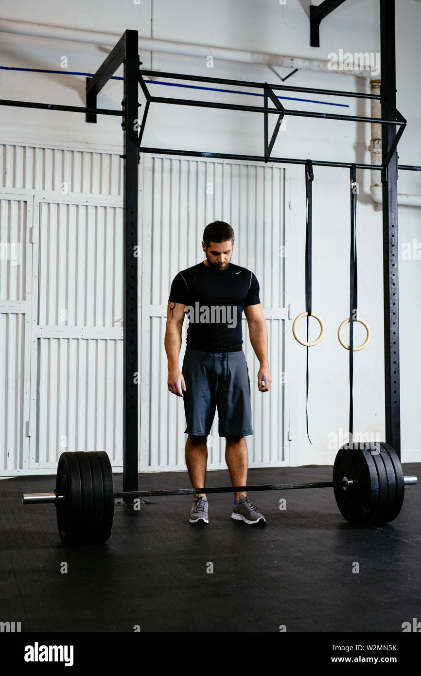 Portrait of athletic man standing over barbell before lifting Stock ...