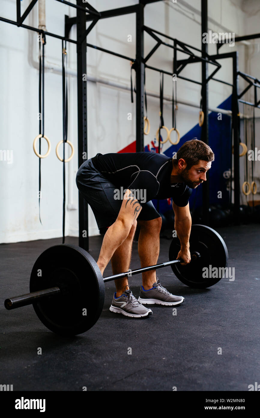 Muscular man holding barbell before lifting Stock Photo - Alamy