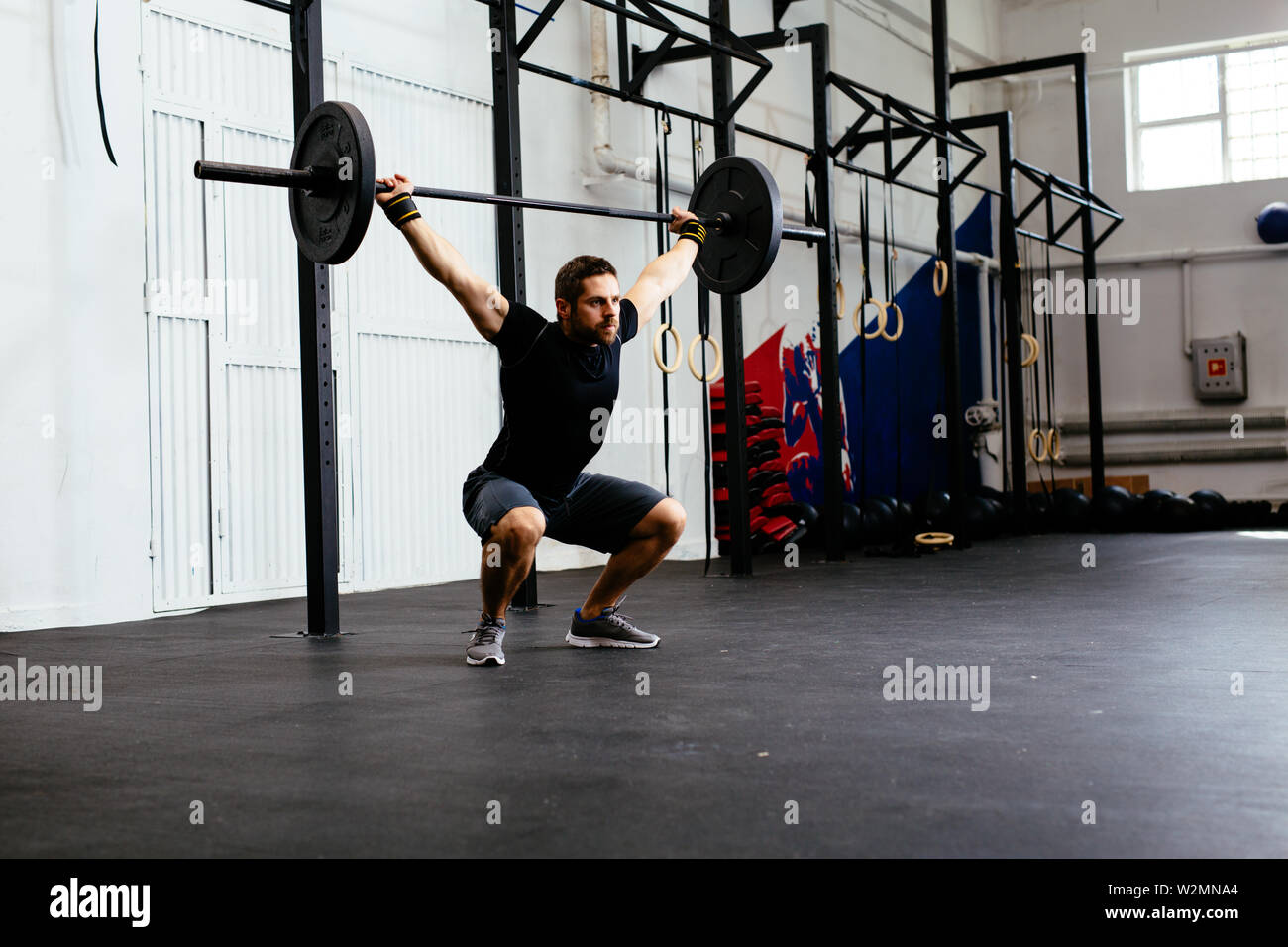 Picture of handsome athlete lifting weights in modern gym Stock Photo ...