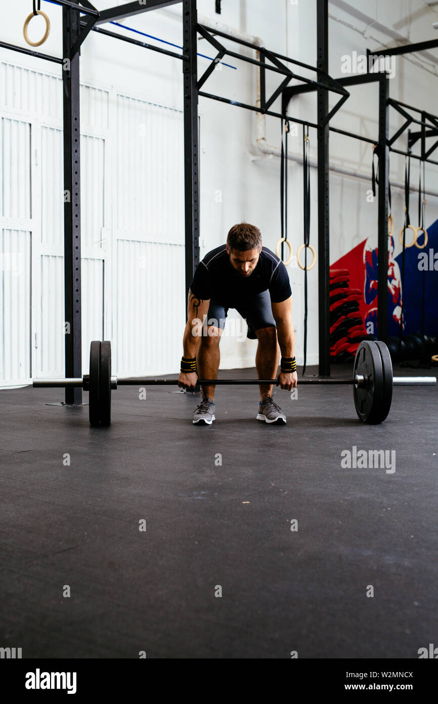 Front view of athletic man lifting barbell in gym Stock Photo - Alamy