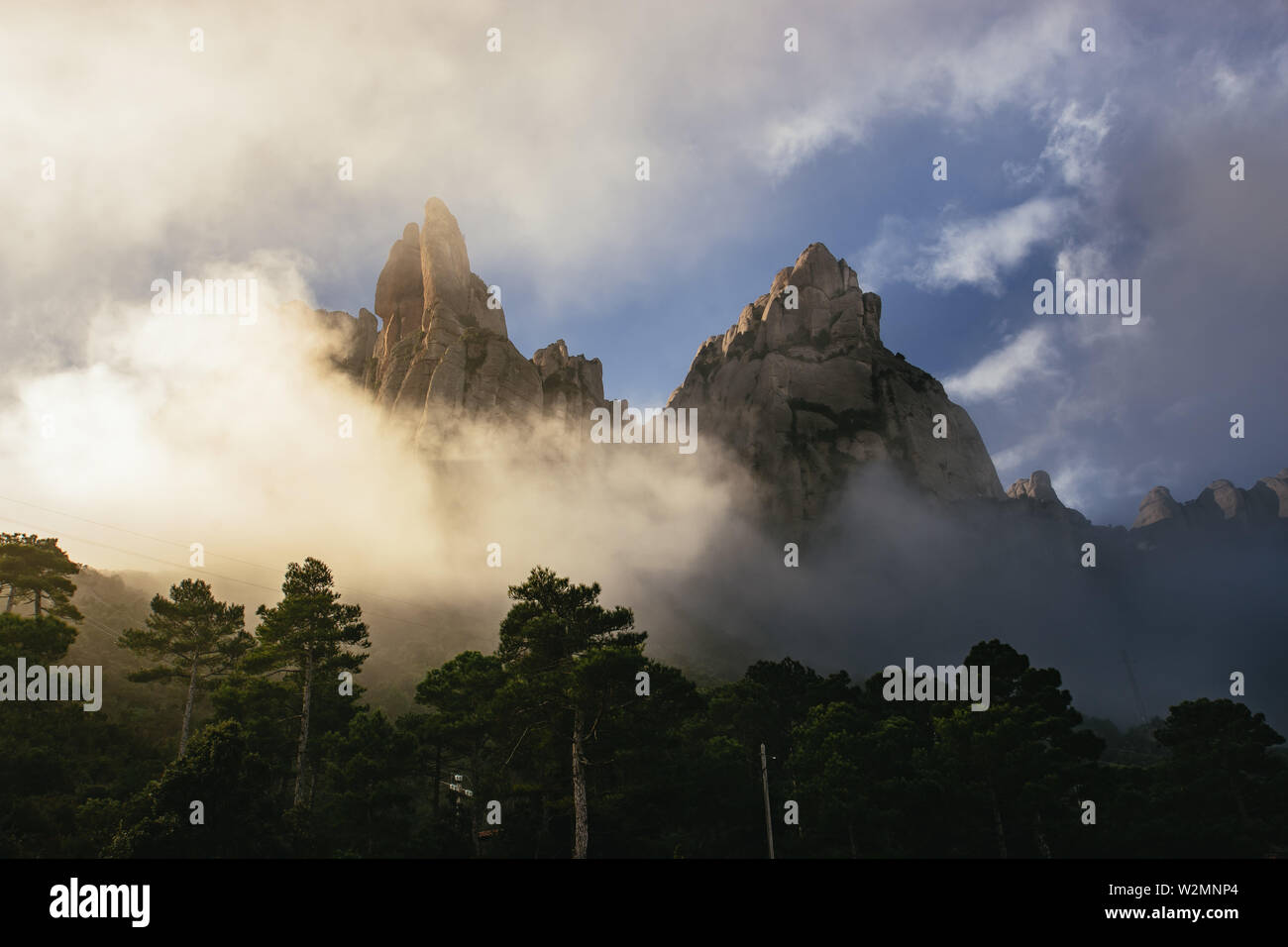 Jagged mountain peaks above a green forest towering above low lying ...