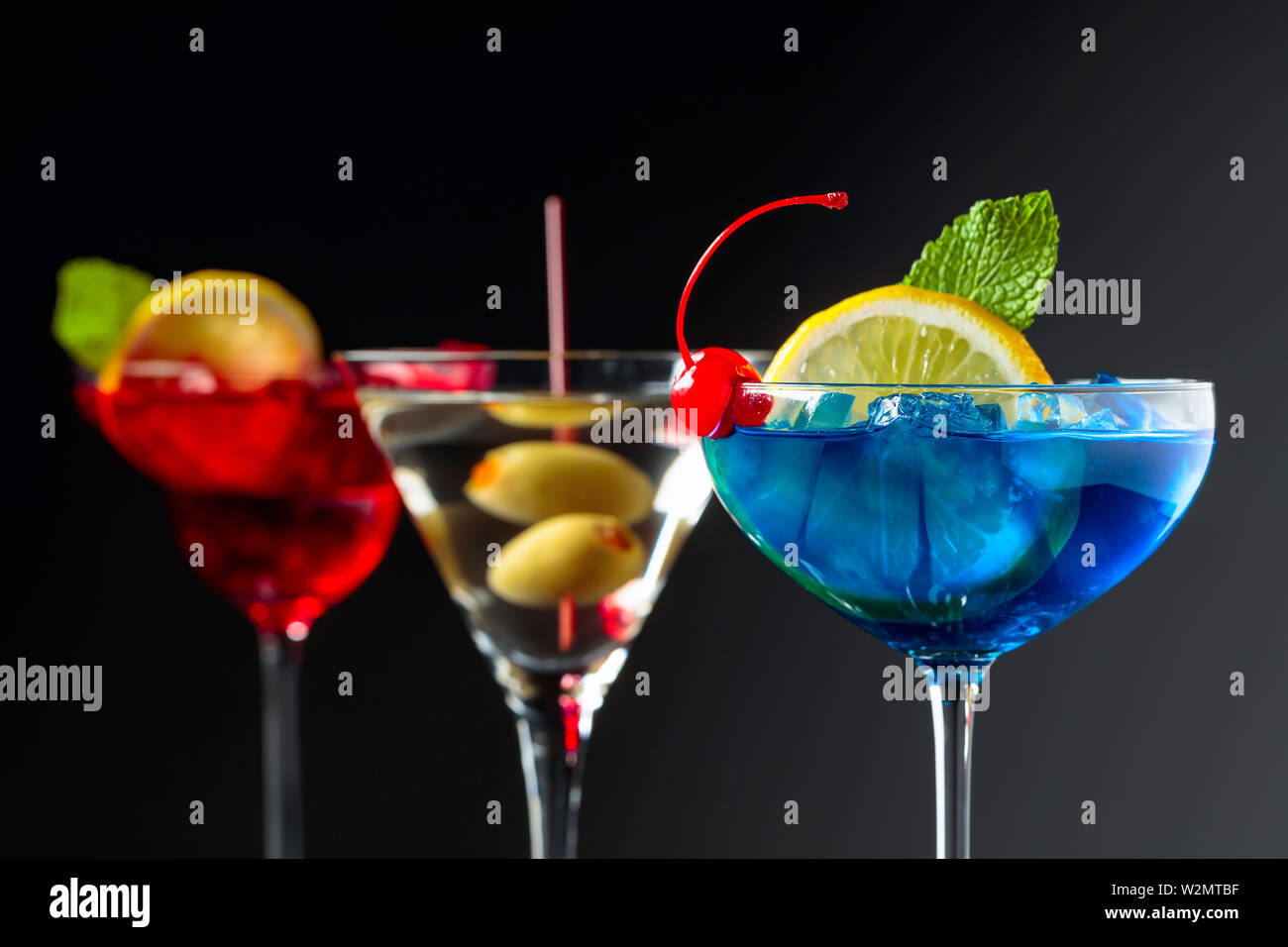 Two colorful cocktails and dry martini with green olives. Red and blue ...