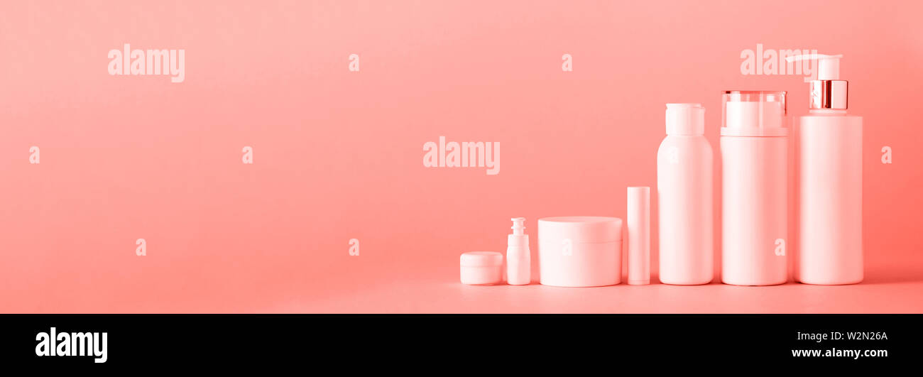 White cosmetic tubes on trendy coral color background with copy space ...