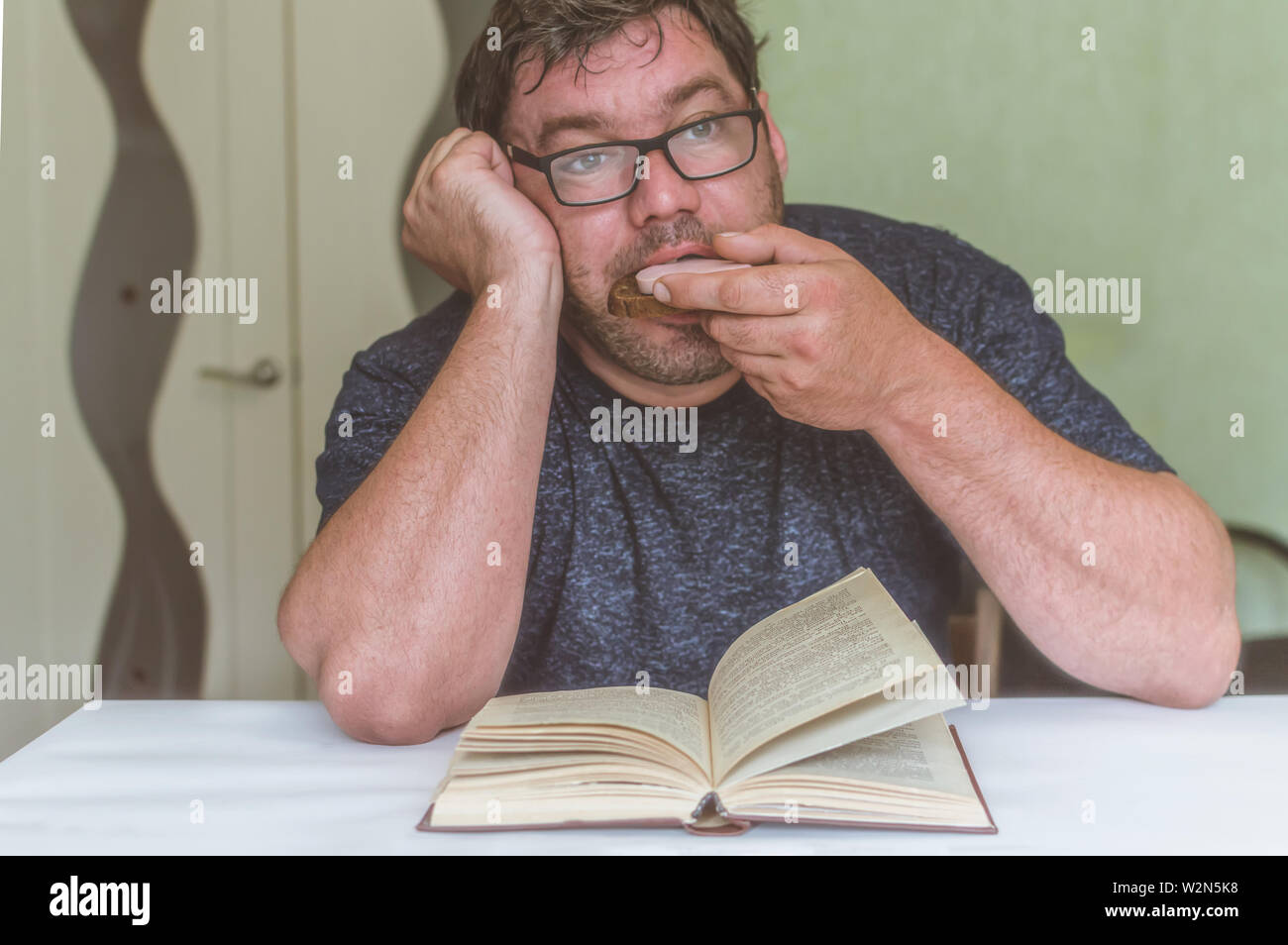 man reading a book at the table, having a snack while reading, a short ...