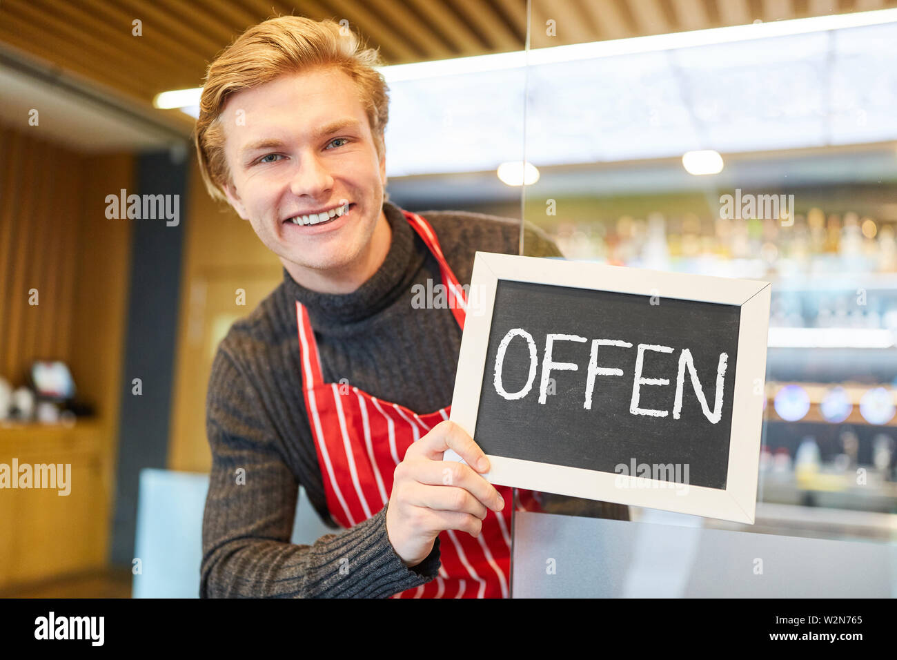 Entrepreneur at restaurant opening holding German "offen" (open) sign ...