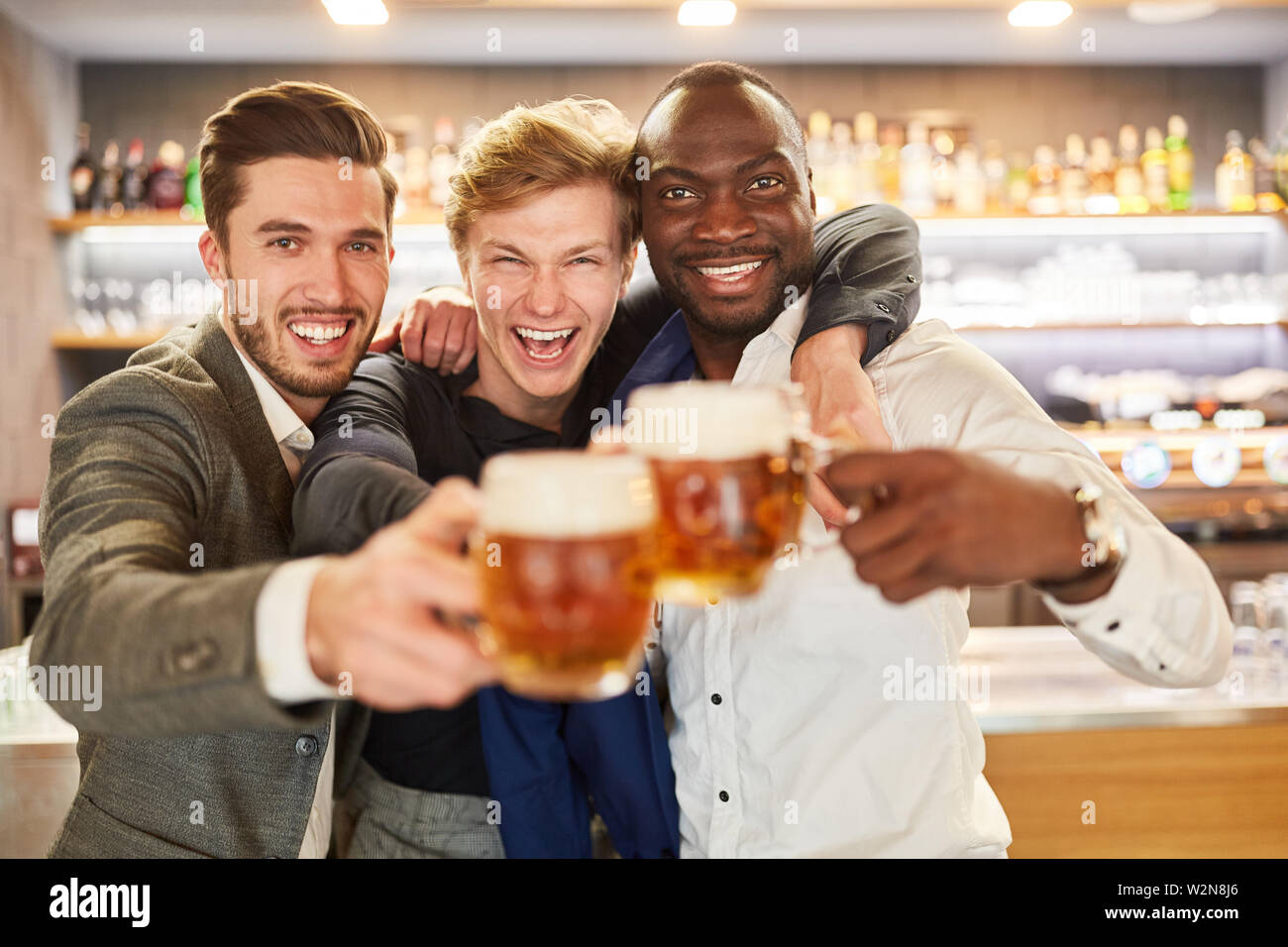 Three men as best friends celebrate hilariously with beer on a pub ...