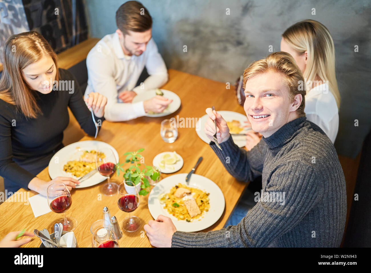 Group of young people having lunch or dinner in restaurant or bistro ...