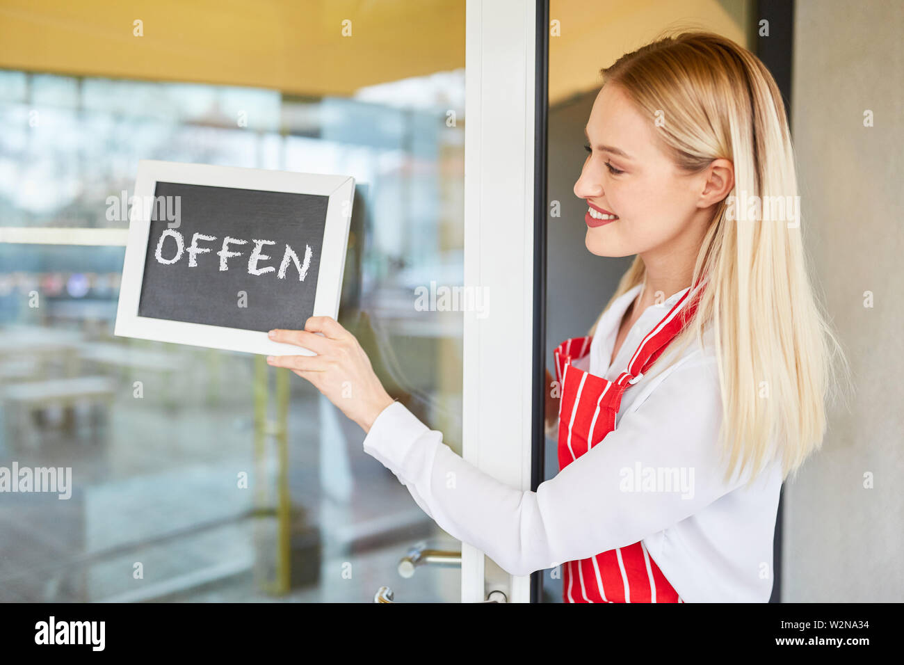 Waitress hangs German "offen" (open) sign at a restaurant Stock Photo ...