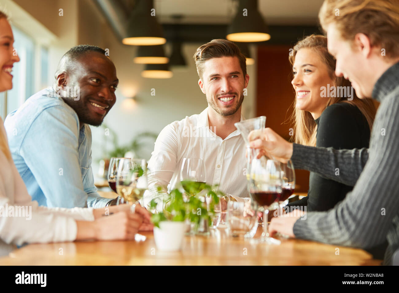 Group of friends meets for small talk over a glass of wine in the ...
