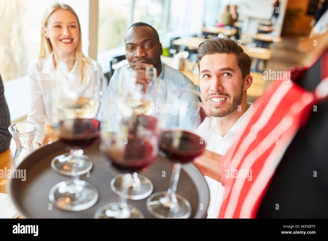 Group of guests in the restaurant or bistro are served by a waitress ...