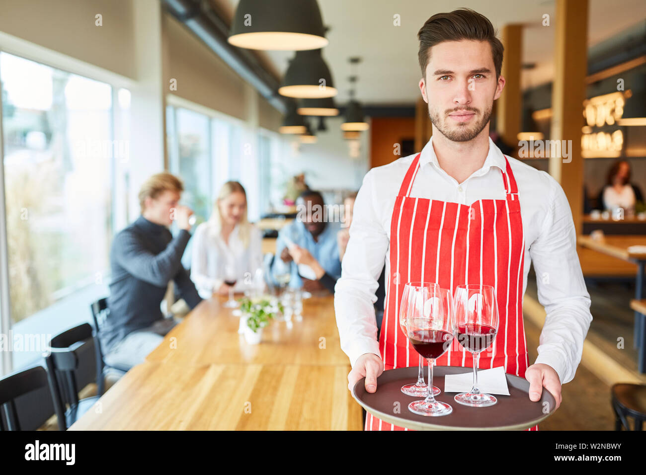 Young man serving as a waiter in training serves wine on a tray Stock ...