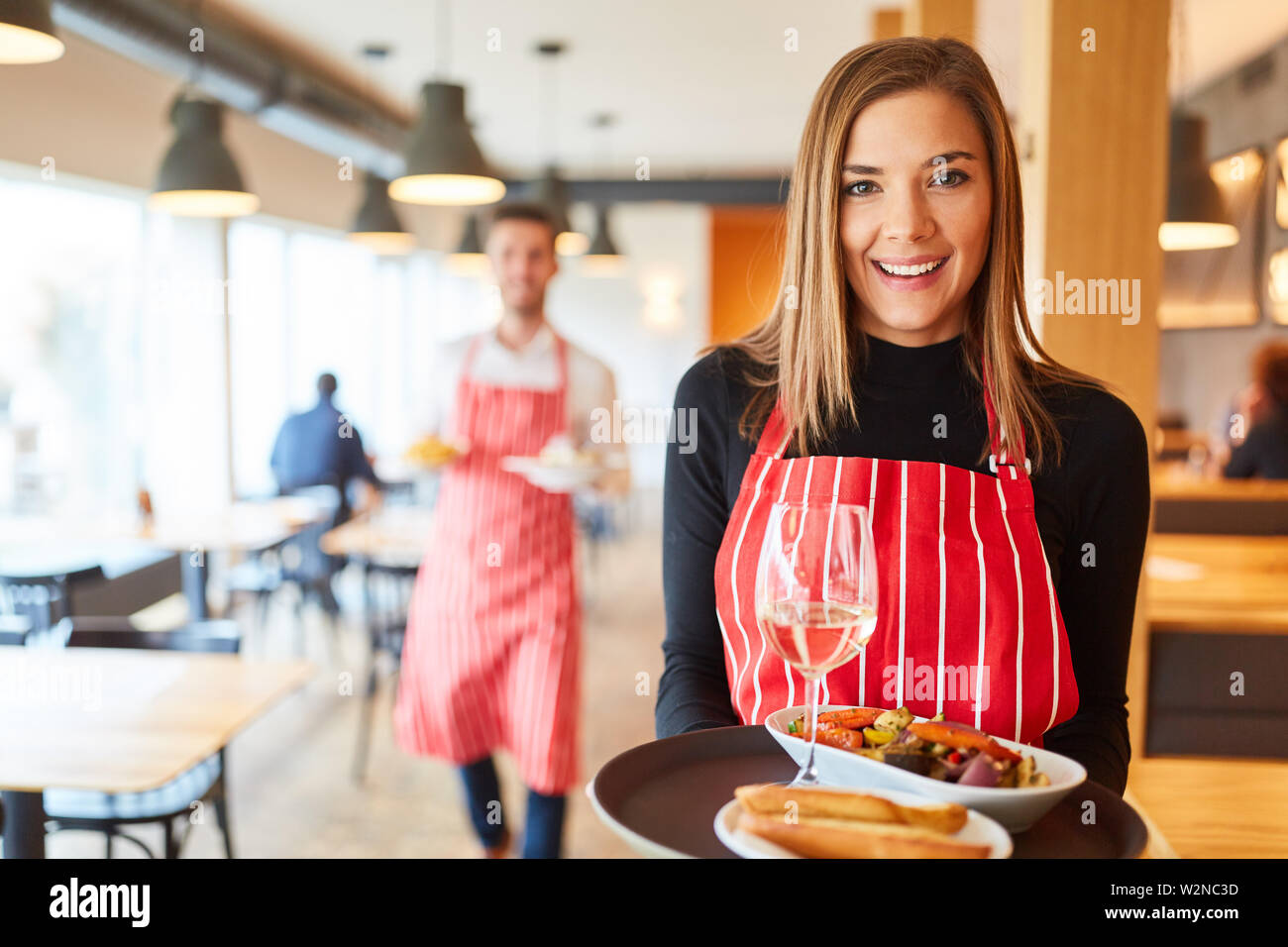 Young smiling woman serving as a waitress serves appetizers in the ...