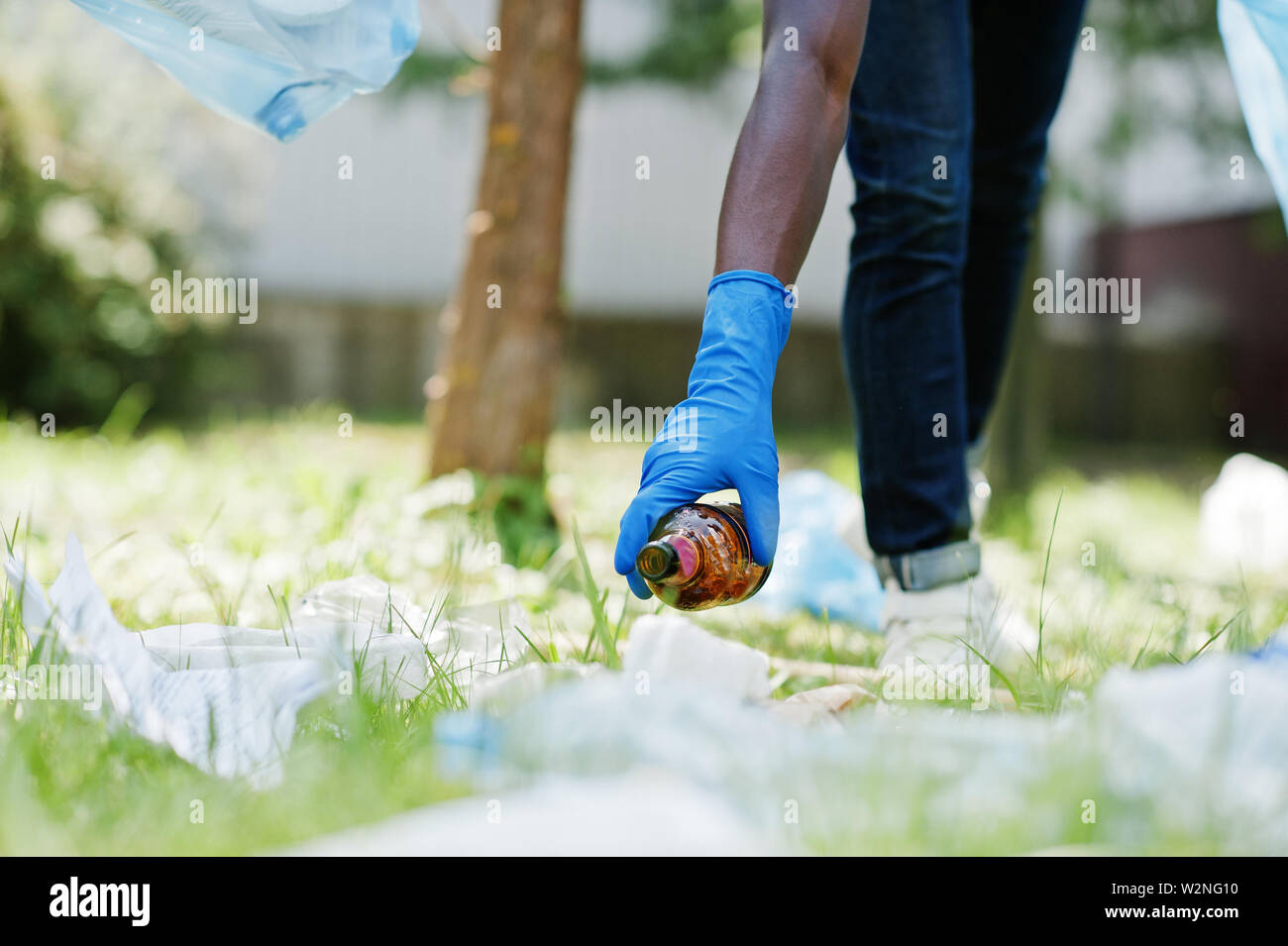 Hand of african american man picking up bottle into garbage bags while ...