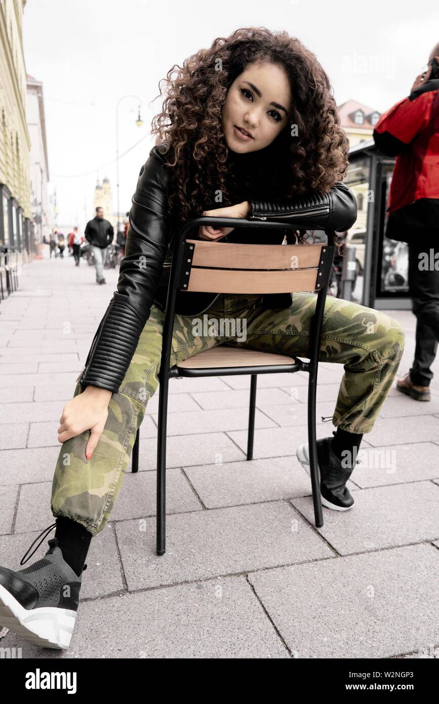 Woman Sitting On Chair At Pavement Wrong Way Round In Munich Germany Stock Photo Alamy
