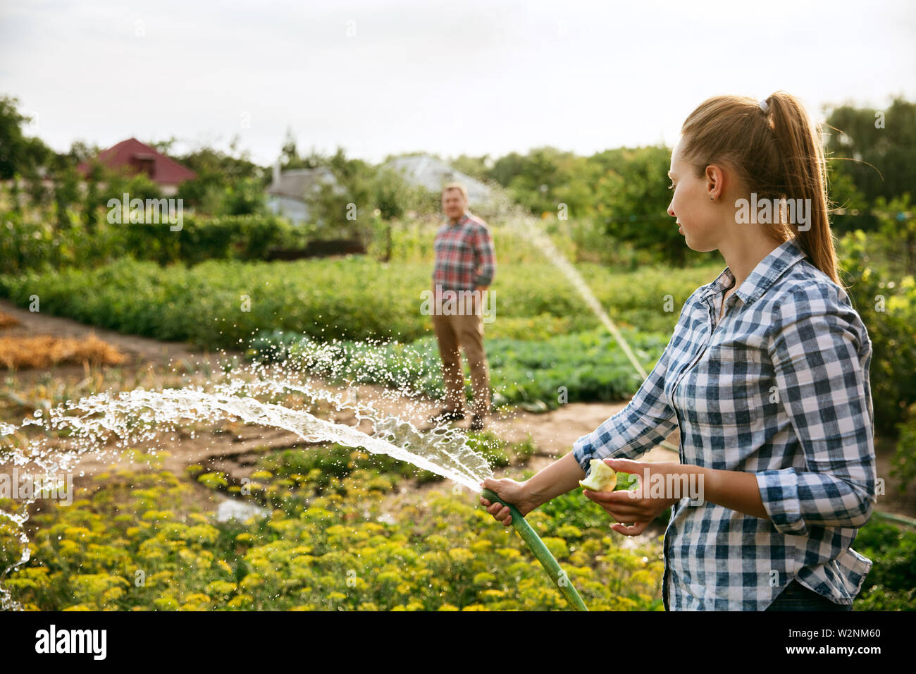 Young and happy farmer's couple at their garden in sunny day. Man and ...