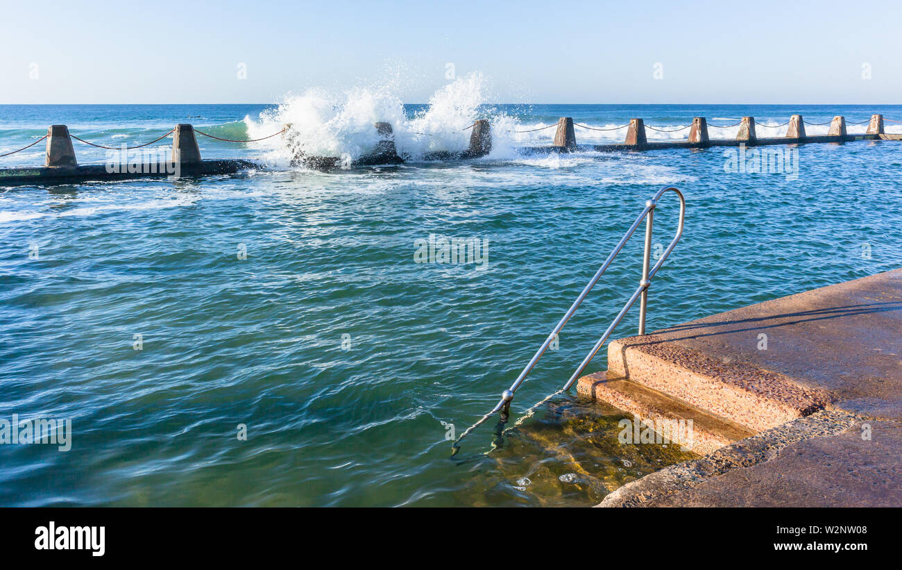 Beach tidal swimming pool with ocean waves breaking crashing on shallow ...