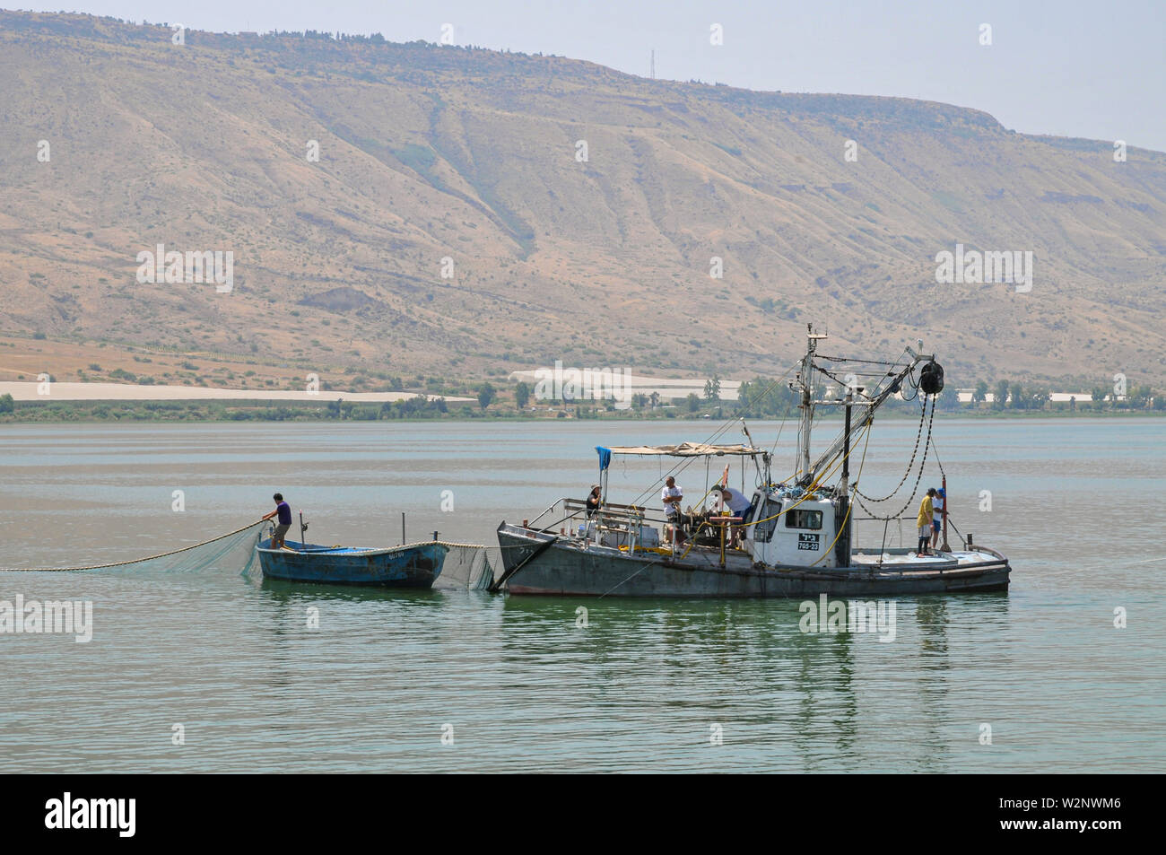 fishing boat and dinghy rounding up fish in a net the Sea of Galilee ...