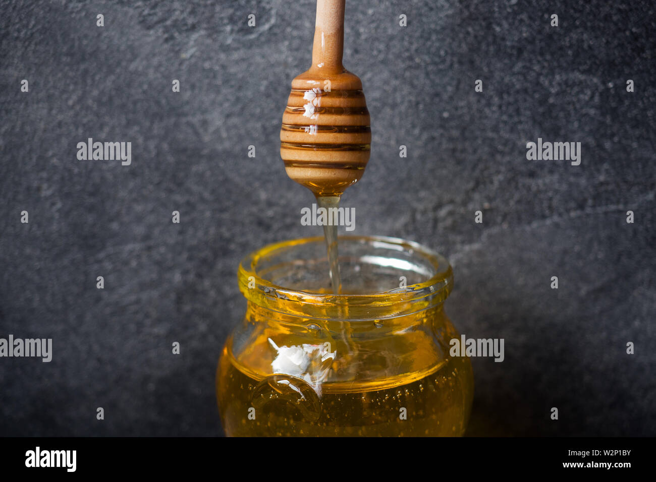 A jar of liquid honey from Linden flowers and a stick with honey on a ...