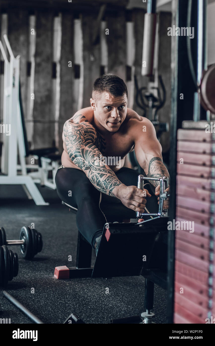 purposeful male bodybuilder performing exercises on the simulator. how ...