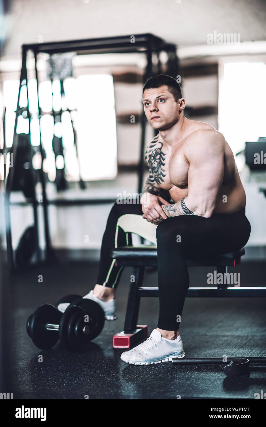 tired male bodybuilder sitting on a bench in a modern gym Stock Photo ...