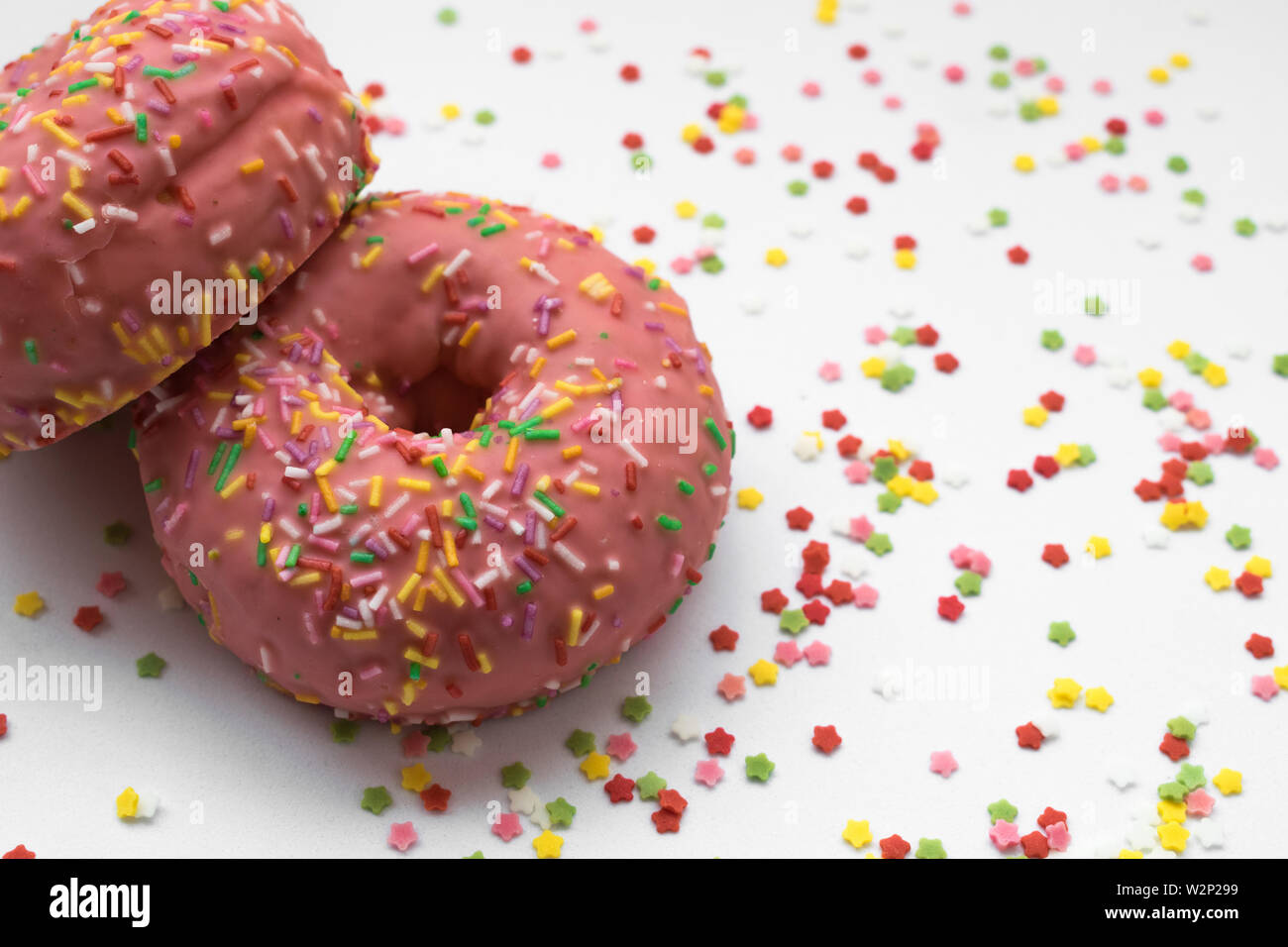 pink donuts with sprinkles on a white background Stock Photo - Alamy