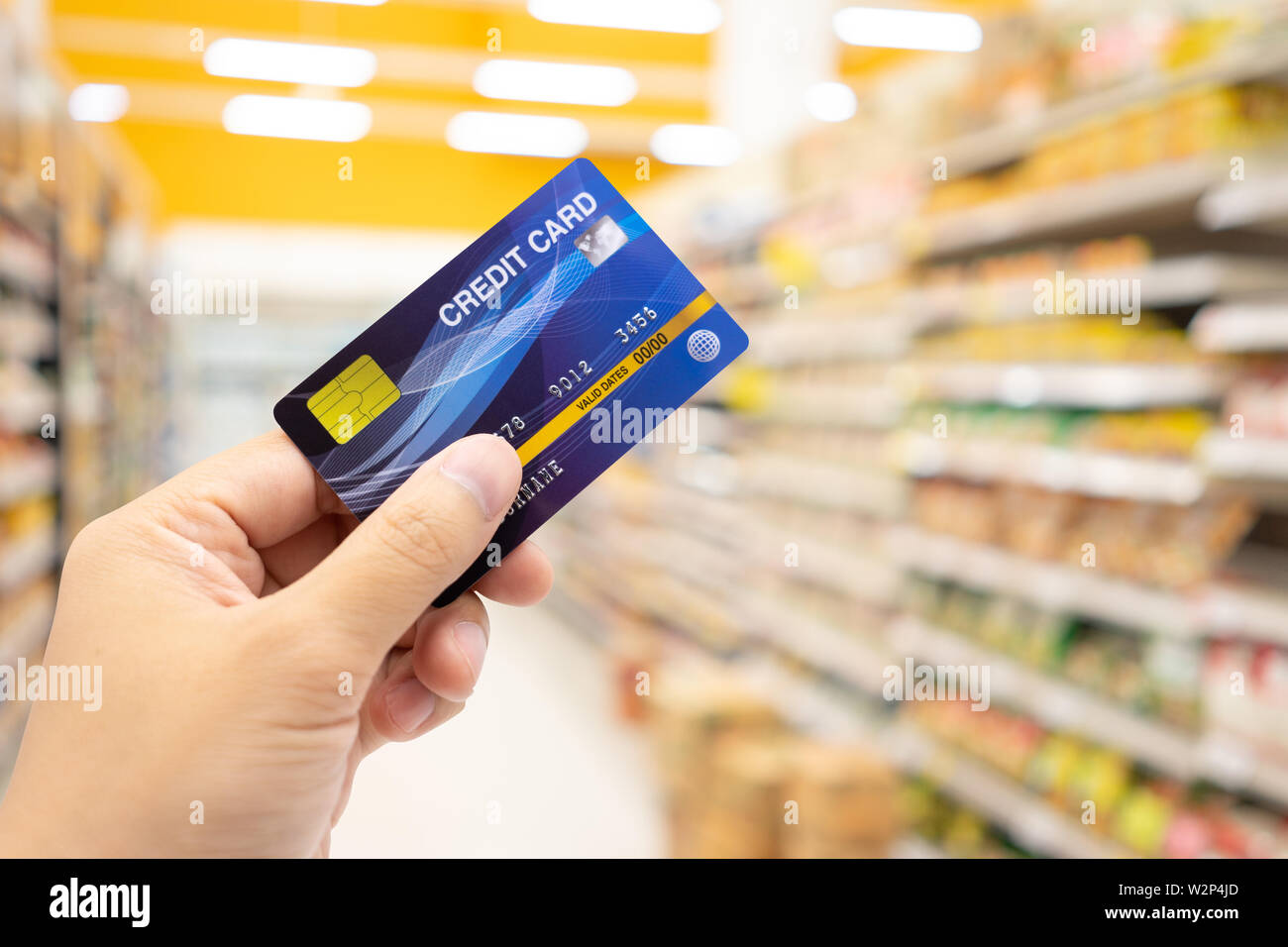 Personal hand holding credit card, with Abstract blurred supermarket ...