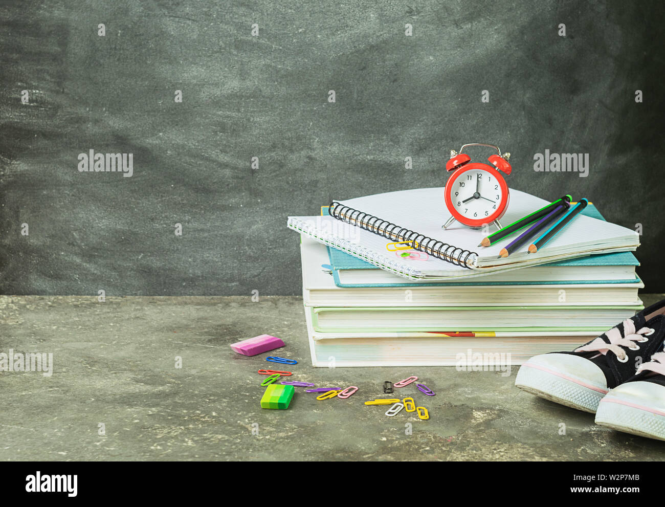 A stack of educational notebooks of books alarm clock on the background ...