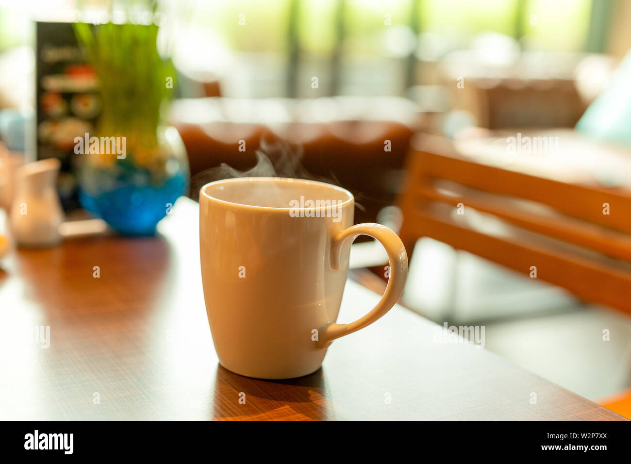 White ceramics coffee mug with smoke and small plant on wooden table in ...