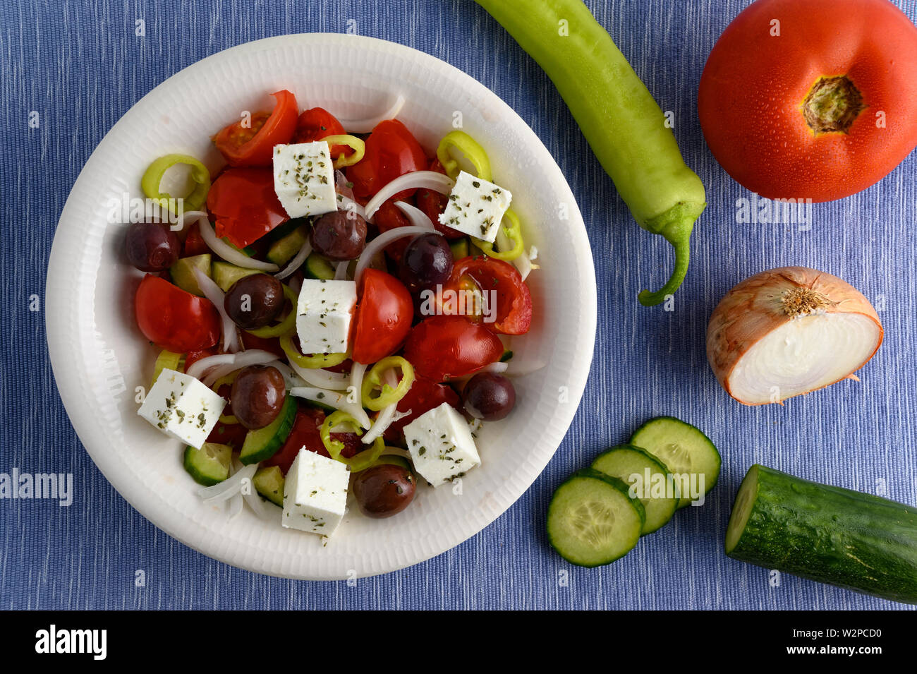 Traditional greek salad in white plate on blue matting Stock Photo - Alamy