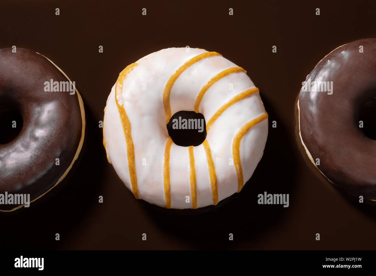 Close-up glazed donuts on dark chocolate background Stock Photo - Alamy