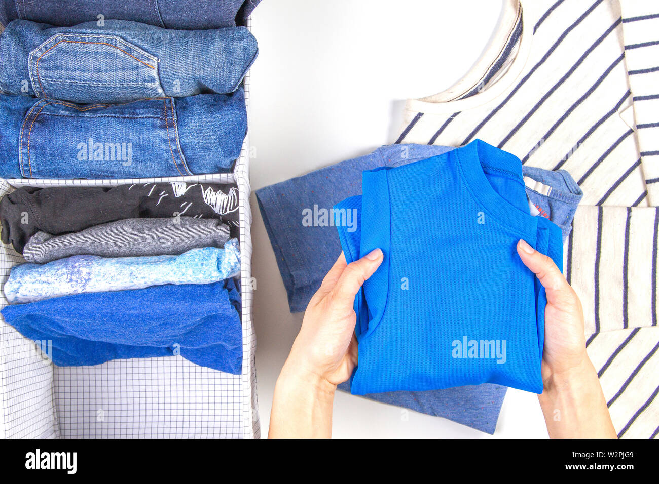 Woman hands tidying up kids clothes in basket. Vertical storage of ...