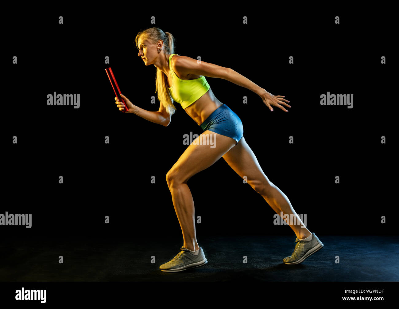 Professional female relay racer training isolated on black studio ...