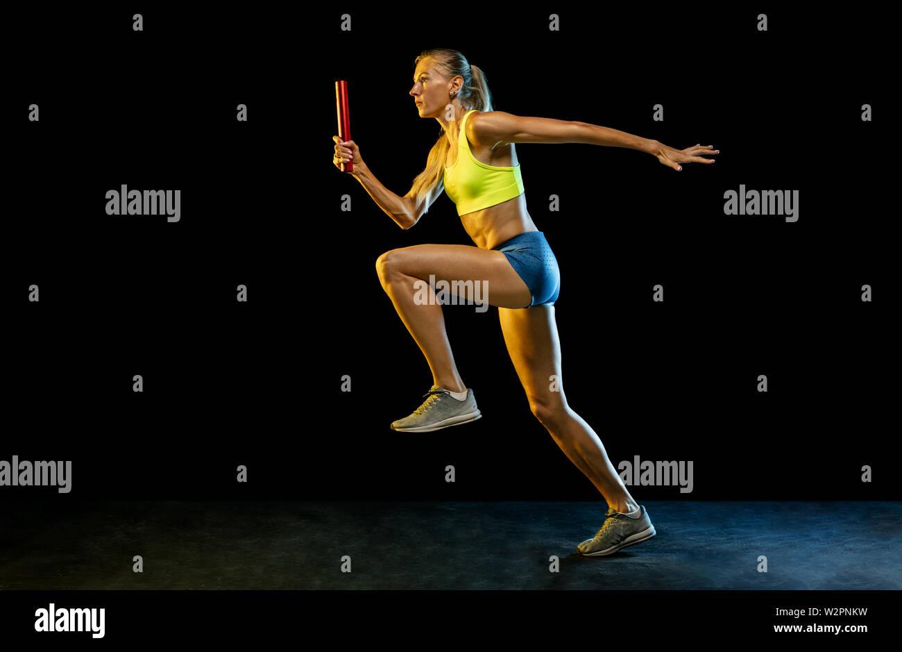 Professional female relay racer training isolated on black studio ...