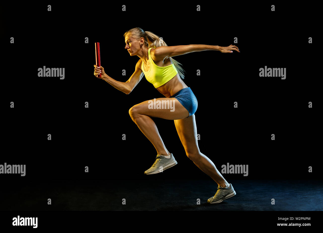 Professional female relay racer training isolated on black studio ...