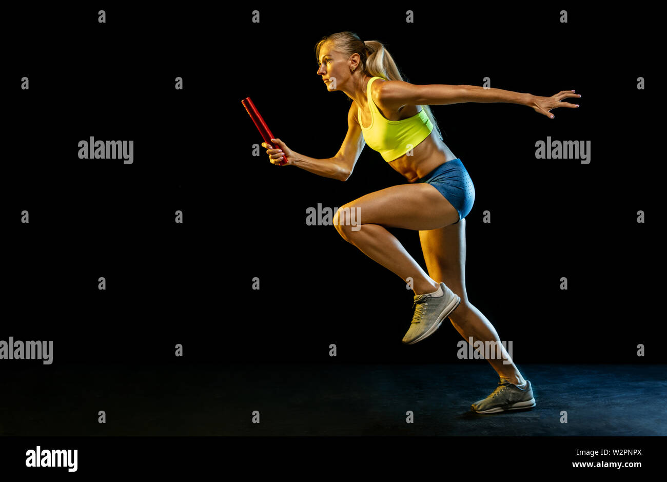 Professional female relay racer training isolated on black studio ...