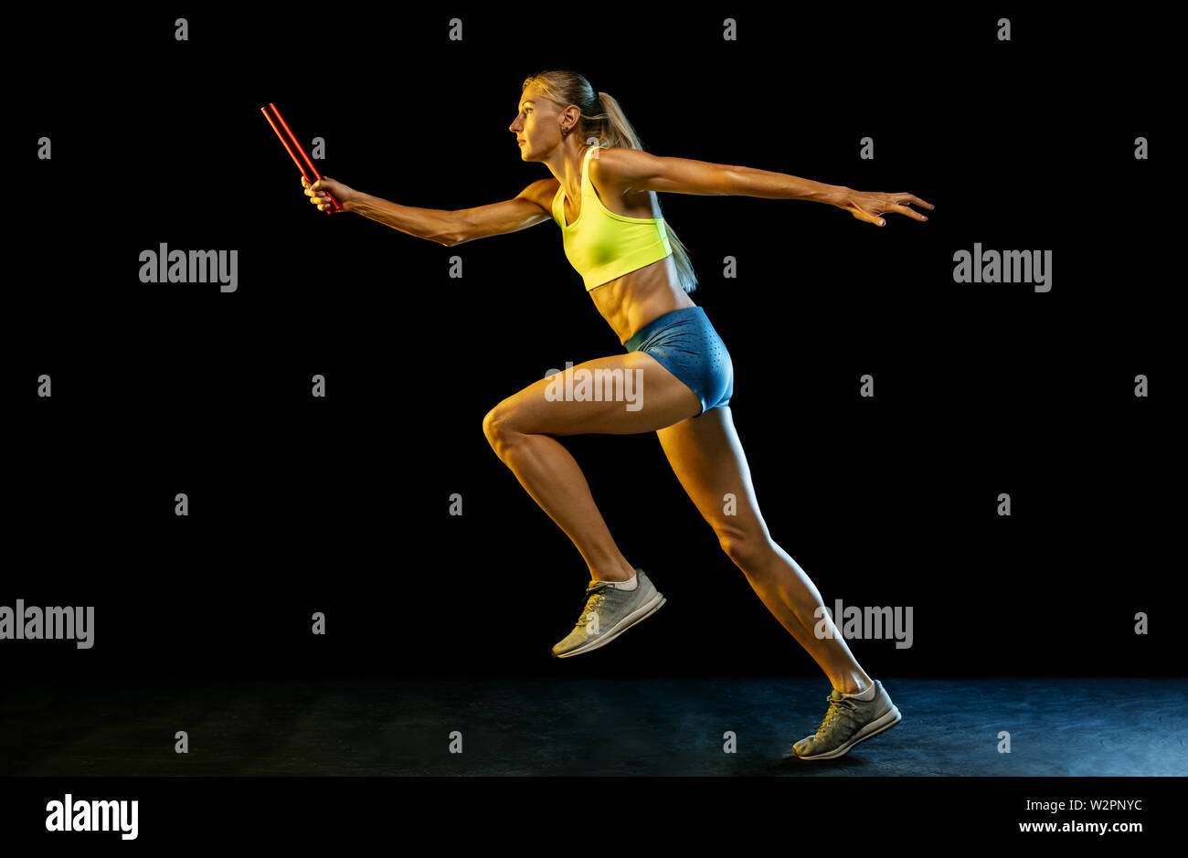 Professional female relay racer training isolated on black studio ...