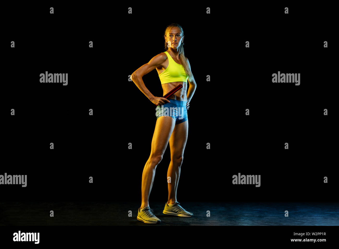 Professional female relay racer training isolated on black studio ...