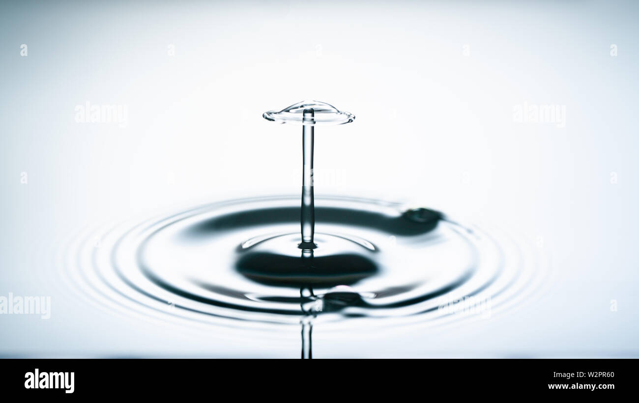 Close-up of a water drop falling on water surface Stock Photo - Alamy