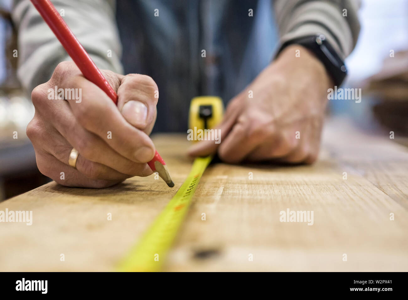 Carpenter measuring and tracing line with a ruler and pencil on wooden ...