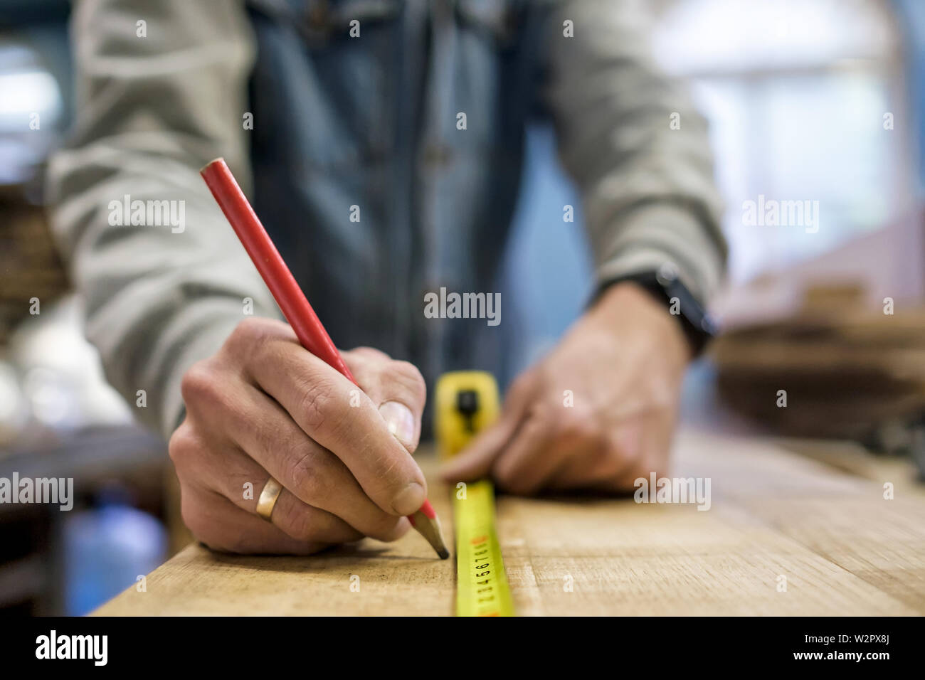 Carpenter measuring and tracing line with a ruler and pencil on wooden ...